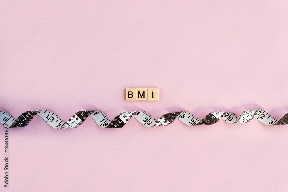 Word BMI on wooden blocks with lettering and measuring tape on pastel ...