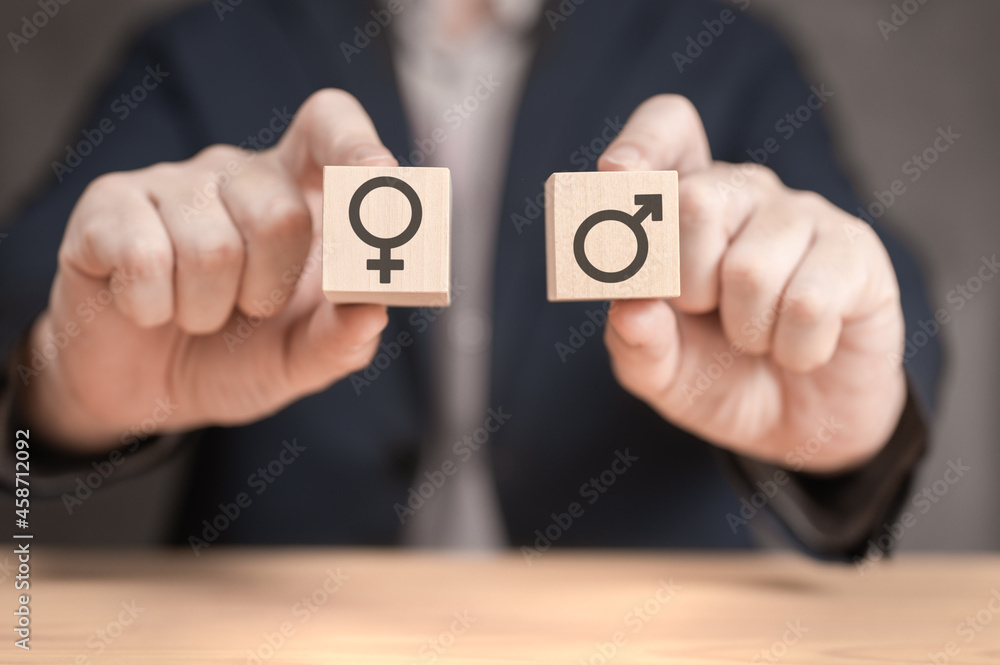 choice between man and woman. hands hold two wooden cubes with male and ...