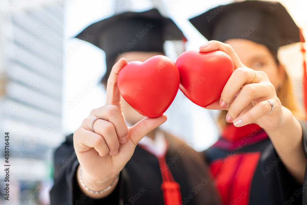 Two red heart in the hand of two girls in a graduation gown. Stock ...