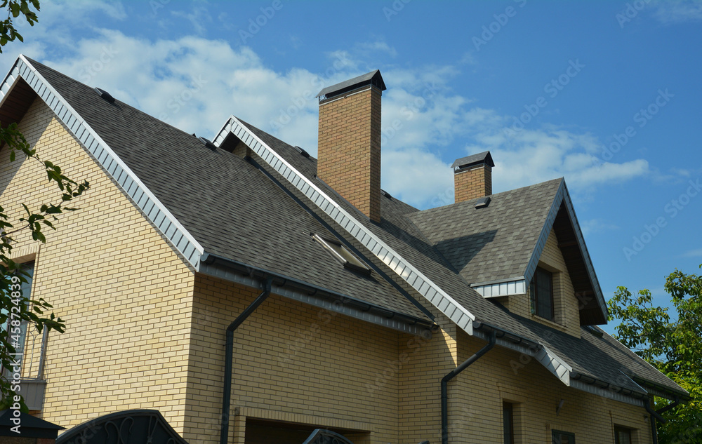 An asphalt shingled roof with skylights, attic windows, chimneys ...