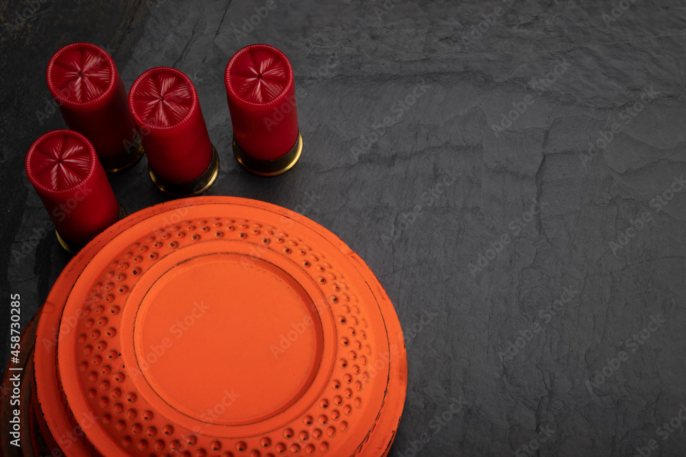 Clay shooting target with shotgun shell on black slate background ...