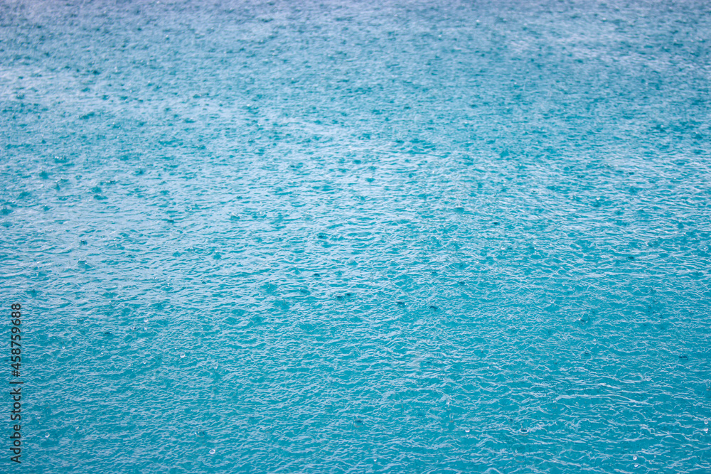Blue water background with rain drops. Downpour drops on water surface ...