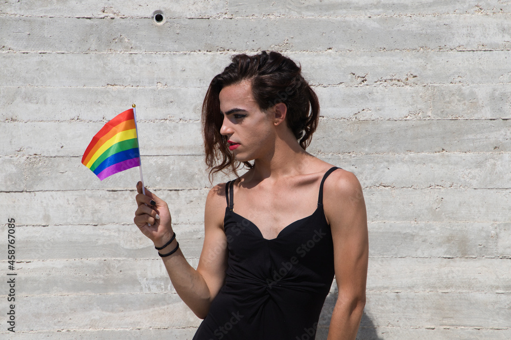 young latin and transsexual woman on grey background holding the gay ...