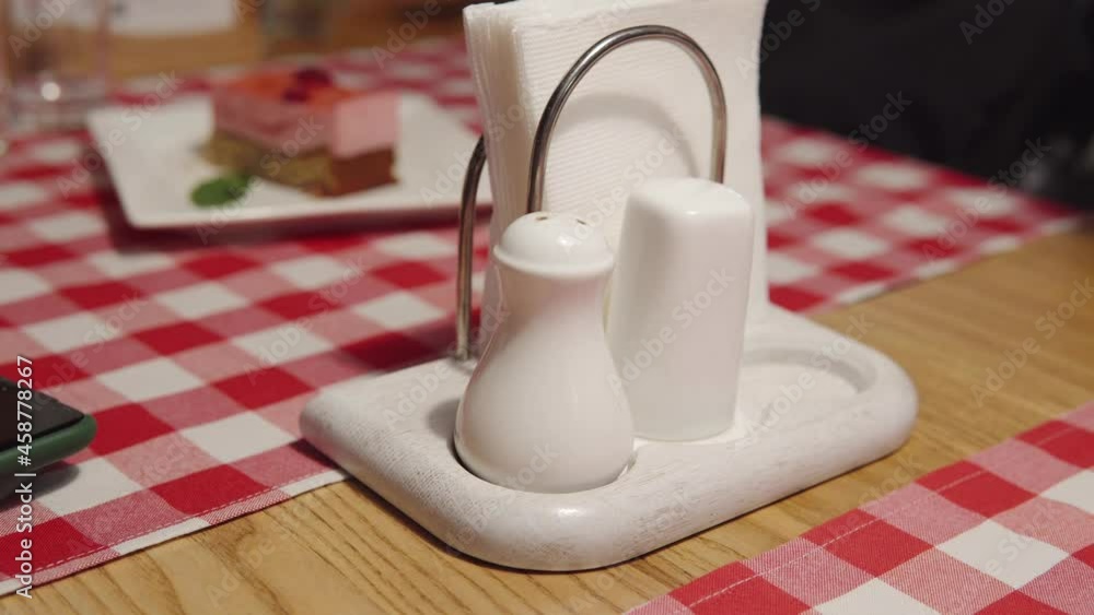 A person takes picks up a container for salt to salt the dish while ...
