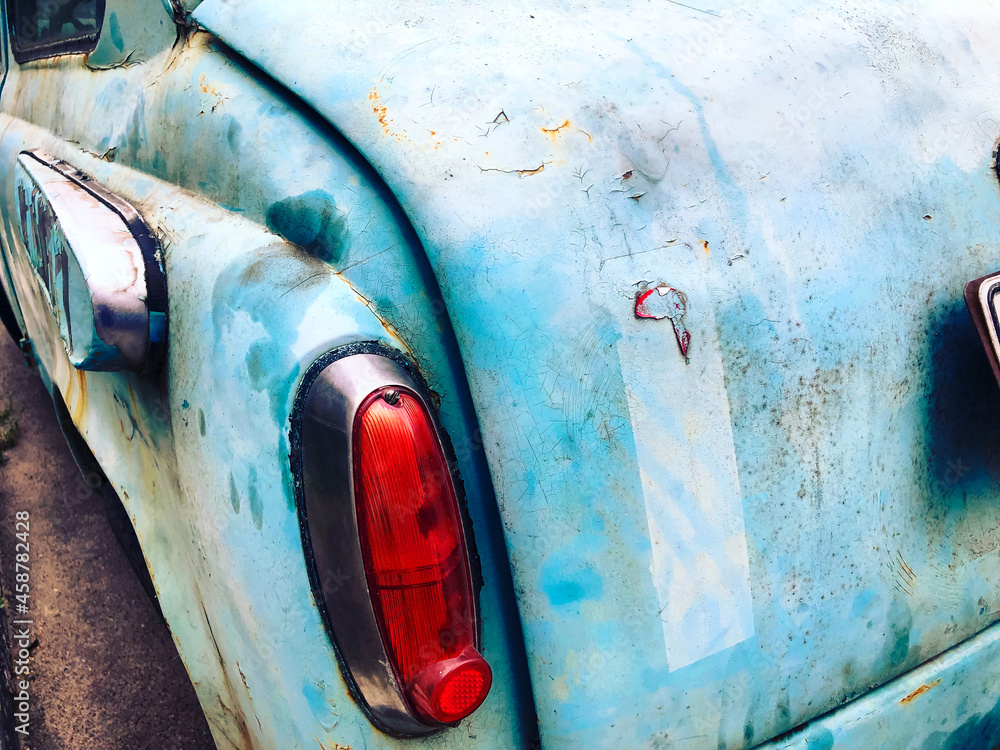 Old rusted abandoned blue retro car, red taillight, peeling paint on ...