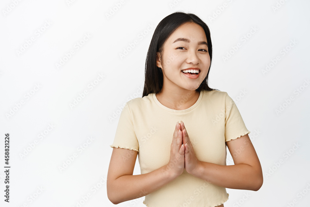 Cute smiling asian girl say thank you, asking for smth, making begging ...