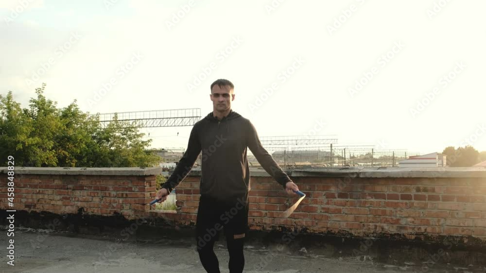 Sporty man jumping with rope training outdoors. man uses skipping rope ...