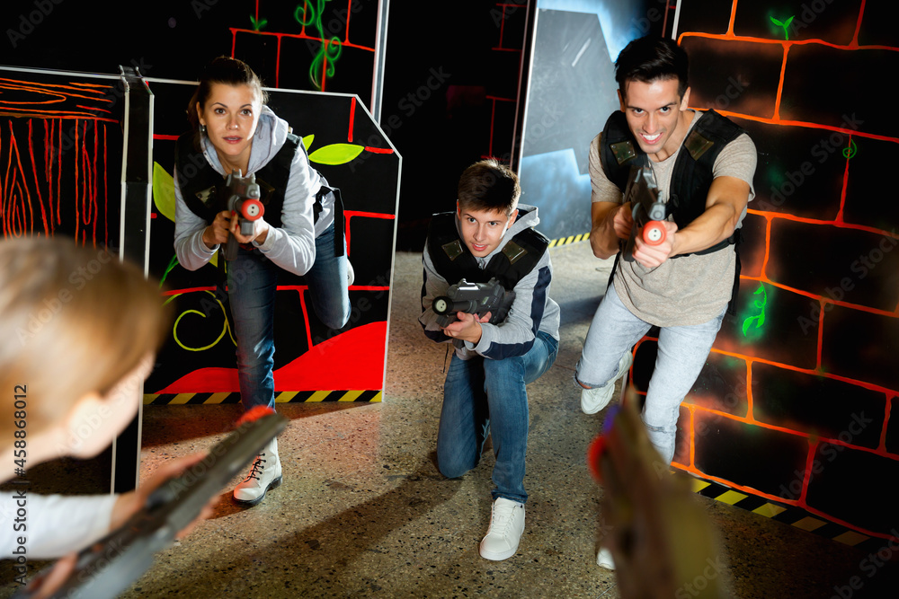 Foto de Ordinary Laser tag players young mens and womens playing in ...