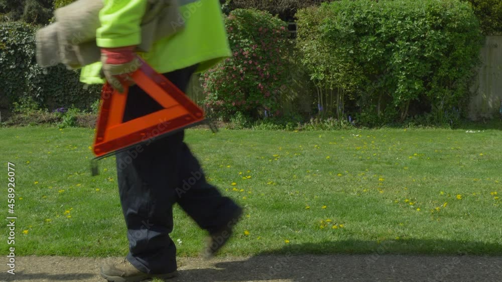 A man wearing a high visibility safety jacket, navy blue overalls, work ...
