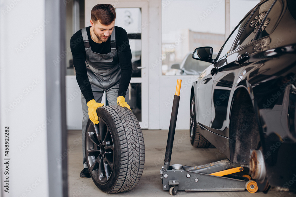 Car mechanic changing wheels in car Stock Photo | Adobe Stock