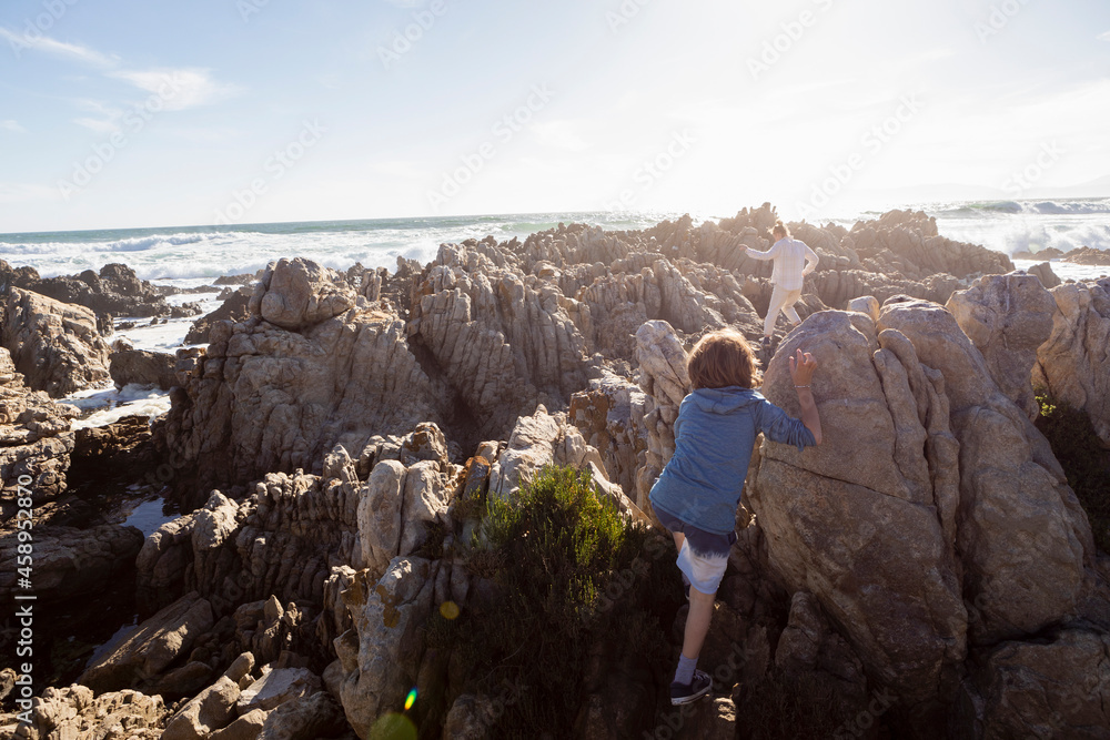 Two children exploring the jagged rocks and rock pools on the Atlantic ...