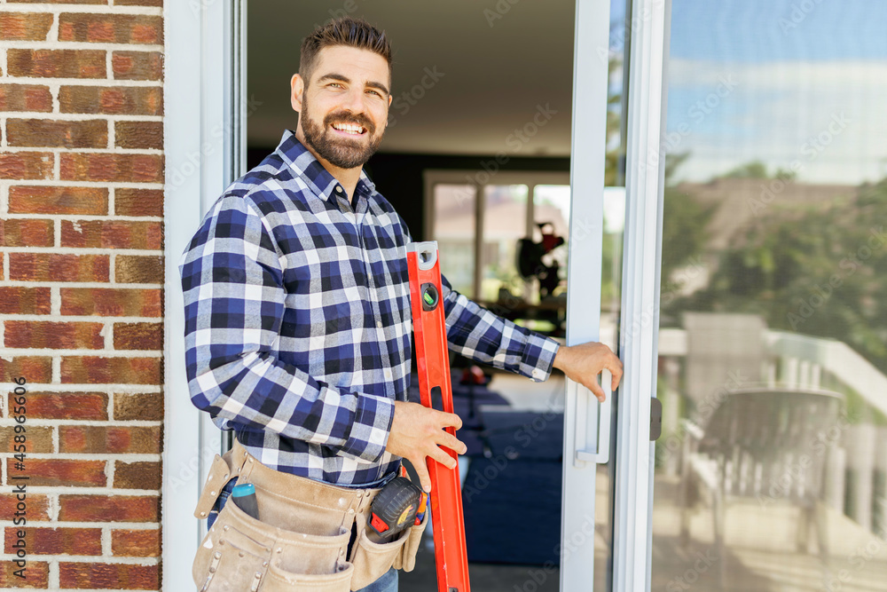 handsome young man installing bay window in a new house construction ...