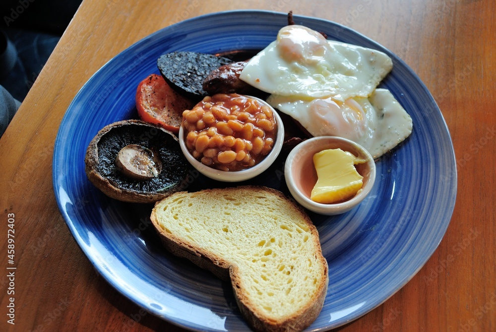 Full English breakfast with a slice of bacon, fried eggs, black pudding ...