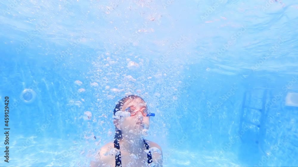 Underwater bubbles slowly rise to water surface from girl swimming in ...