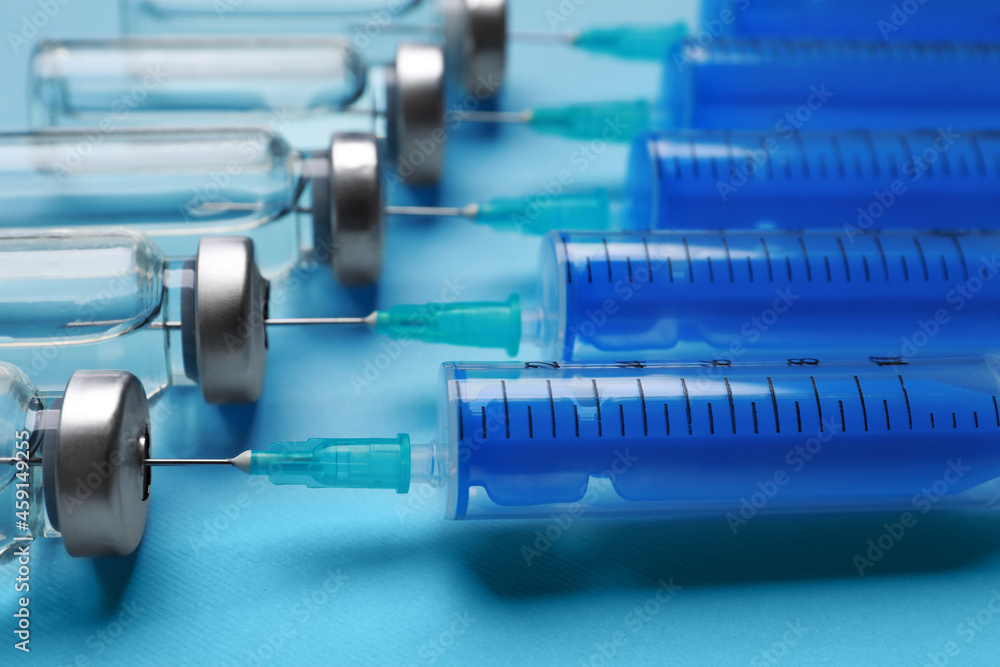 Disposable syringes with needles and vials on light blue background ...