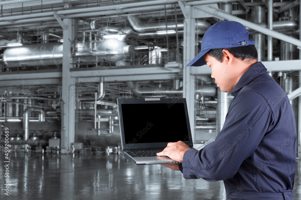 Mechanic working on a computer connected to a machine for maintenance ...