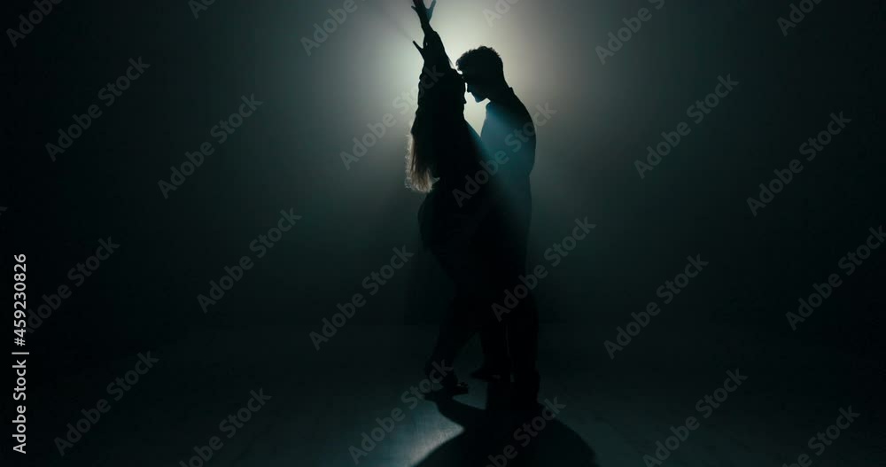 Ballroom dance between two partners shadows of figures on stage in dark ...