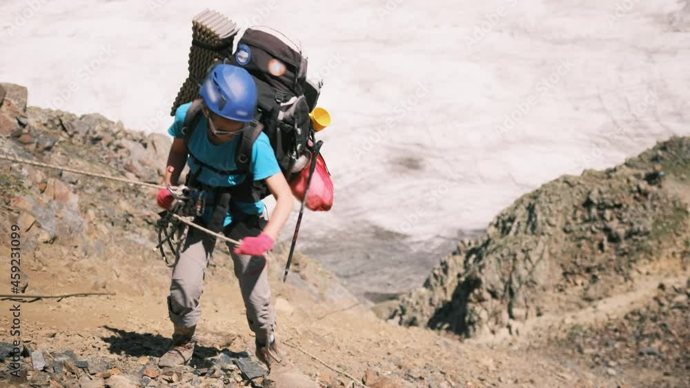 A climber with a large backpack with gear descends from the mountain on ...