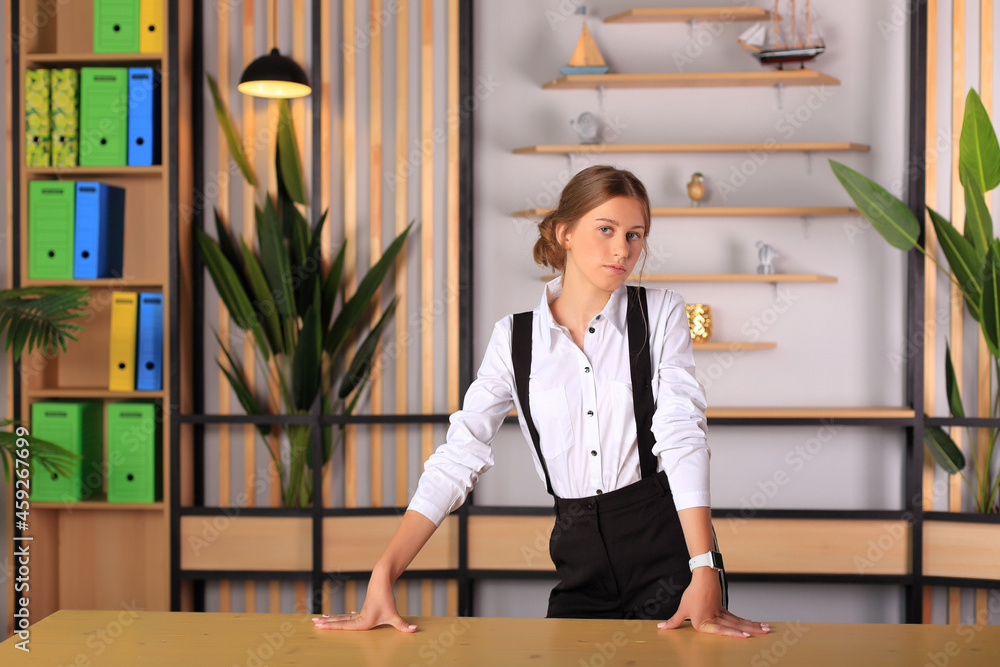 Young beautiful girl in office style looks at the camera. A teenager in ...