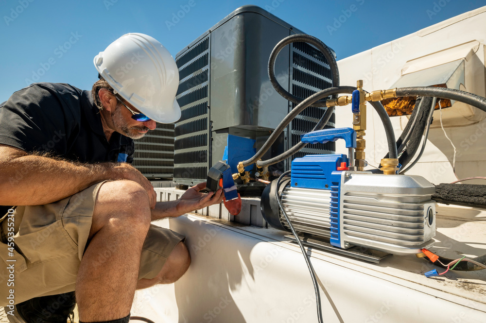 HVAC technician repairing an air conditioner Stock Photo | Adobe Stock