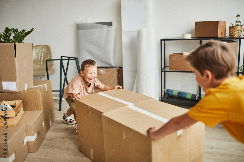 Portrait of two happy boys moving boxes and playing while family ...