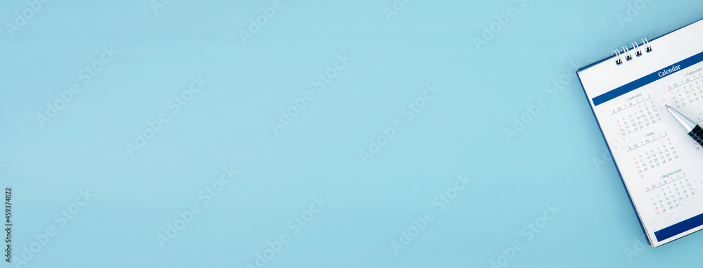 pen and calendar placed on blue background with copy space, business ...