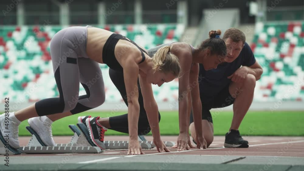 Woman sprinters are training at the stadium, two sporty females are ...