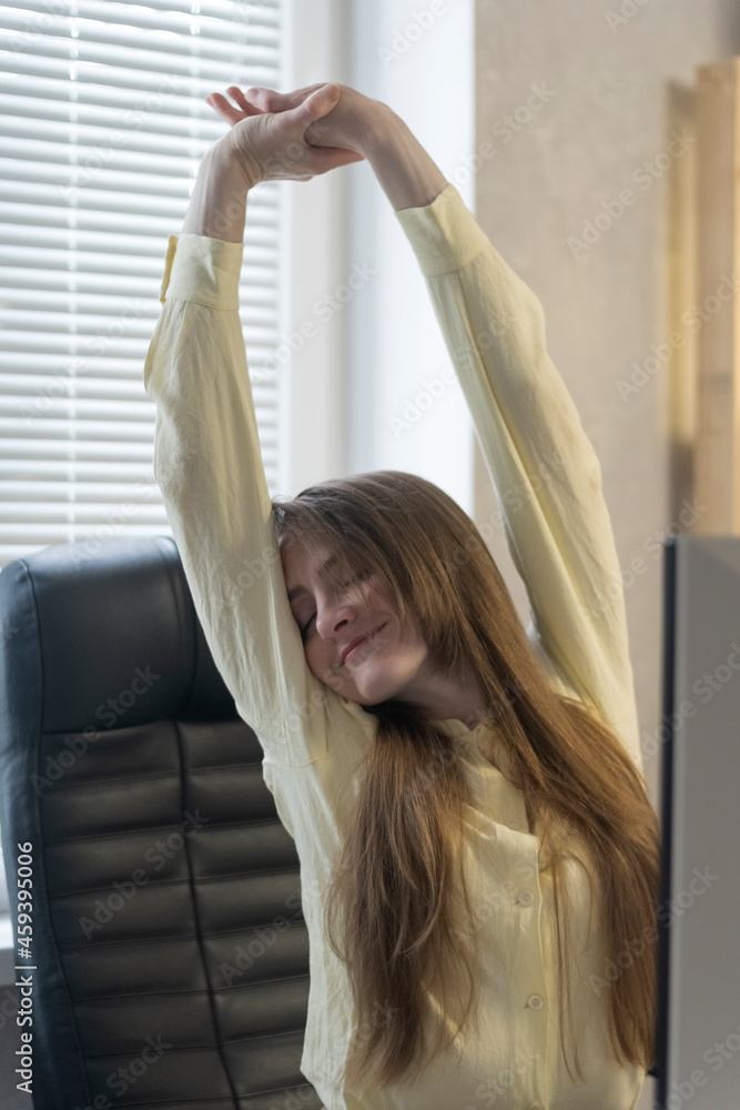 Girl does a warm-up while sitting at the workplace. Back exercises ...