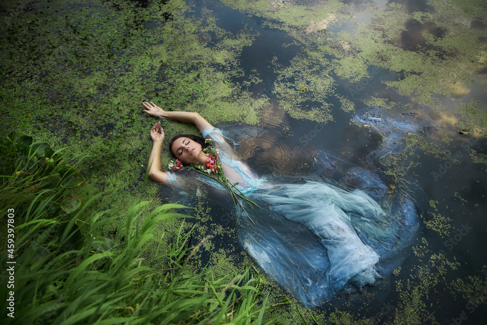 Fotka „Art beautiful romantic woman lies in swamp in blue long dress ...