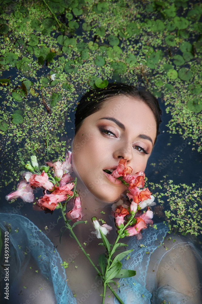 Art beautiful romantic woman lies in swamp in blue long dress with ...