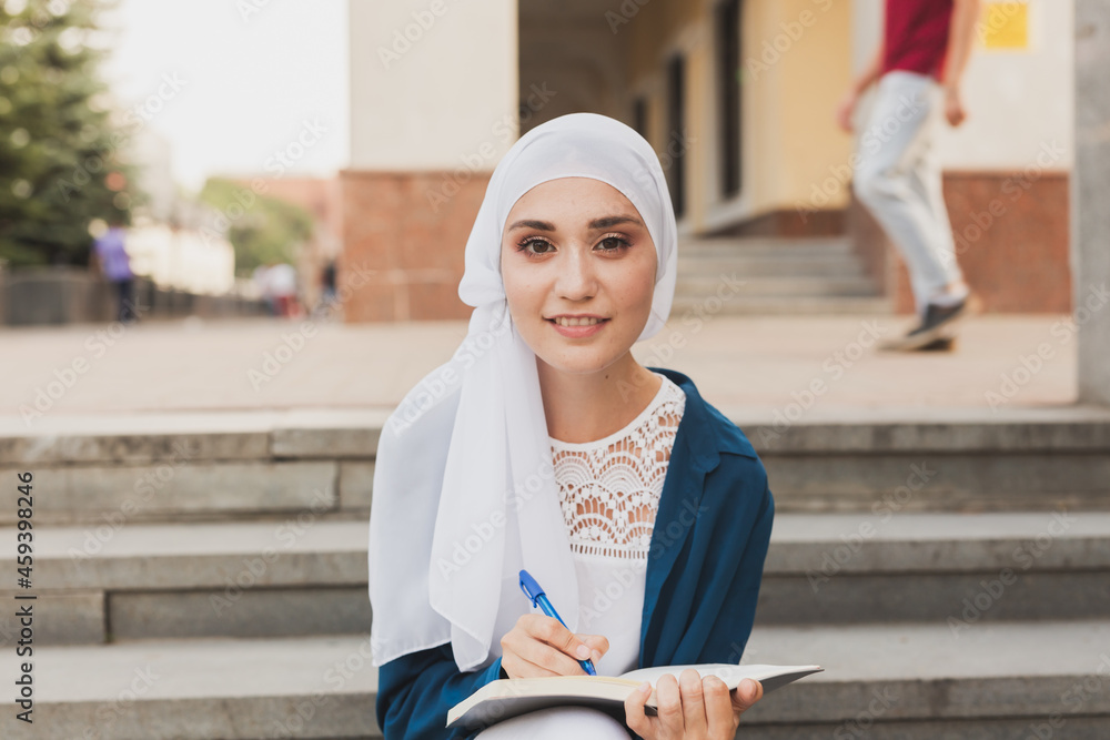 Female middle eastern college student sits on stairs in university ...