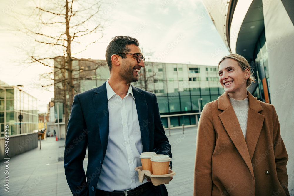 Smiling mixed race colleagues bonding while walking to work enjoying ...