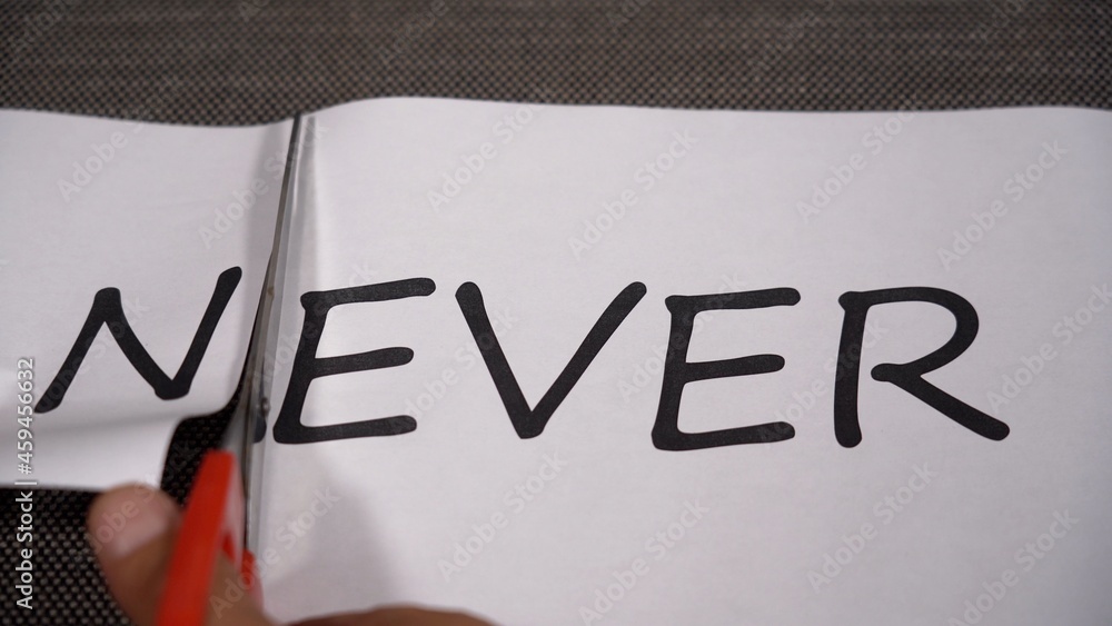 cutting word NEVER to read EVER. Female hand using scissor to express ...