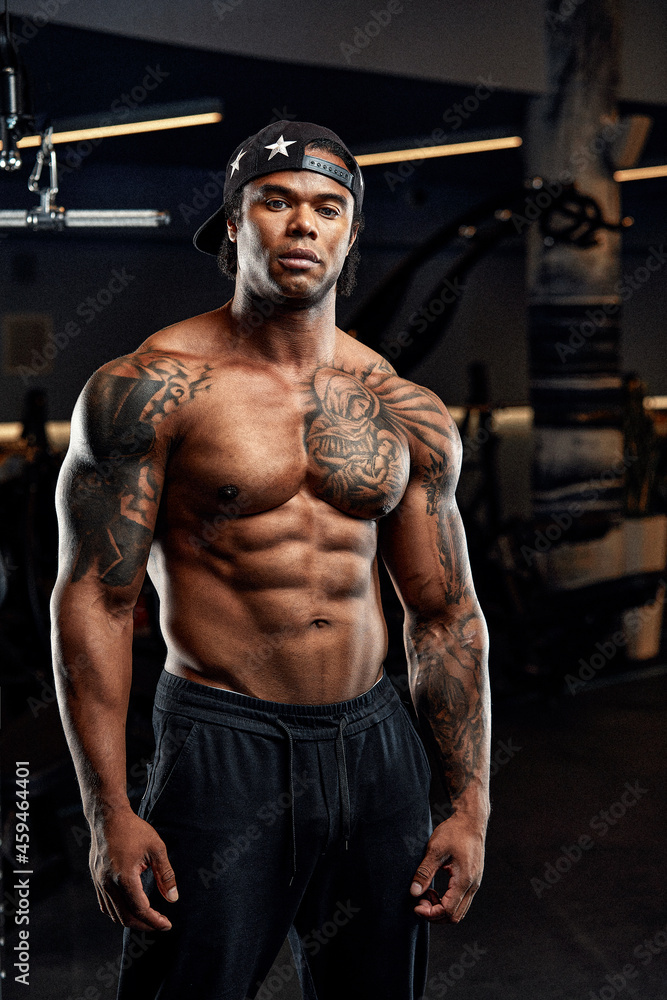 Strong and muscular afro man trains on modern equipment in gym ...