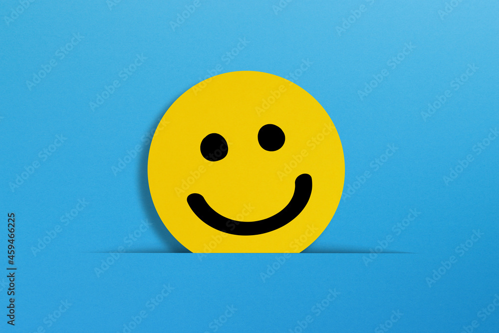 Happy smiley face emoticon coming out of a pocket on a blue background ...