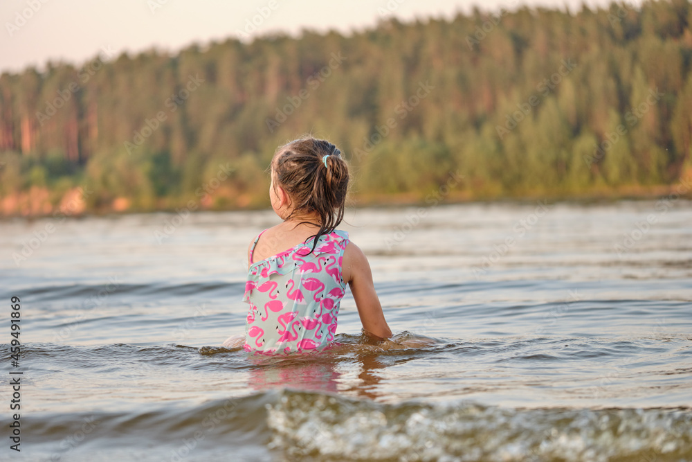 Little girl sits in water in a river lake. A child without a life ...