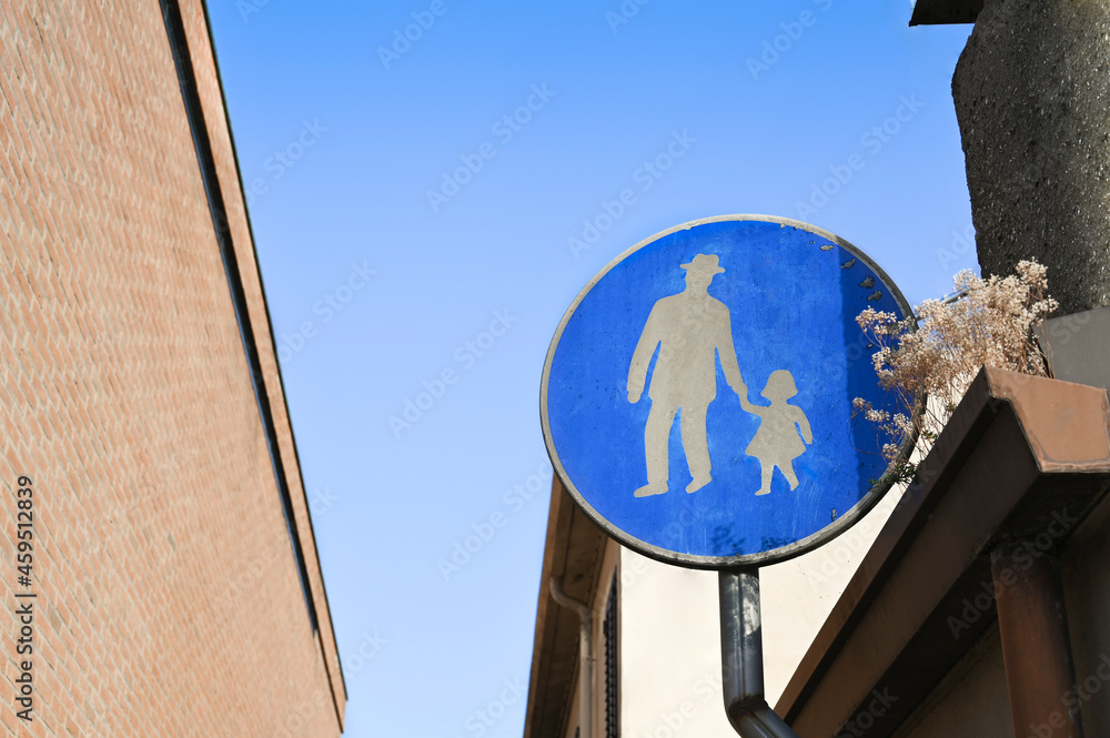 Round sign depicting an elderly man holding a small child by the hand ...