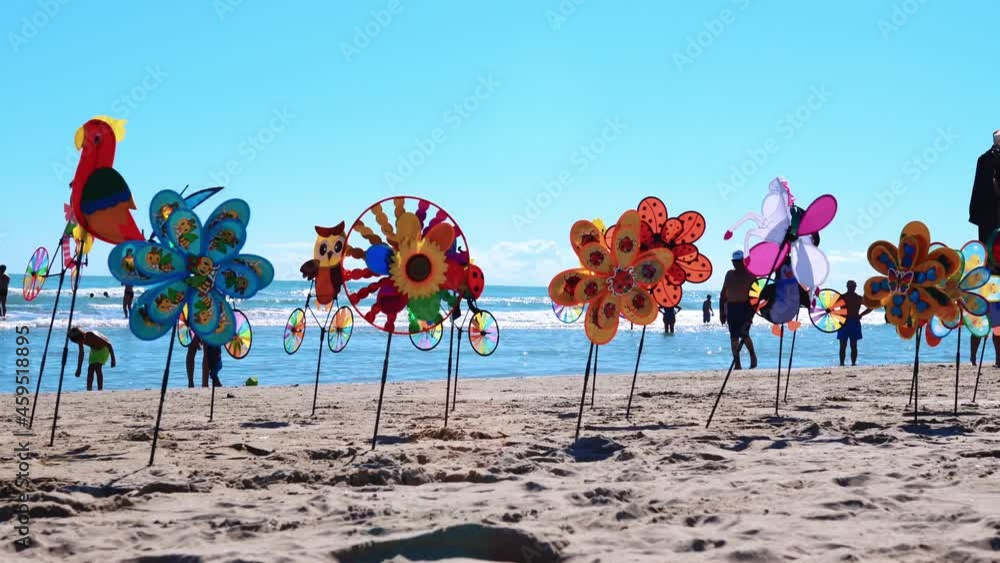 Row of colourful toy windmills blowing in wind on amazing seascape ...