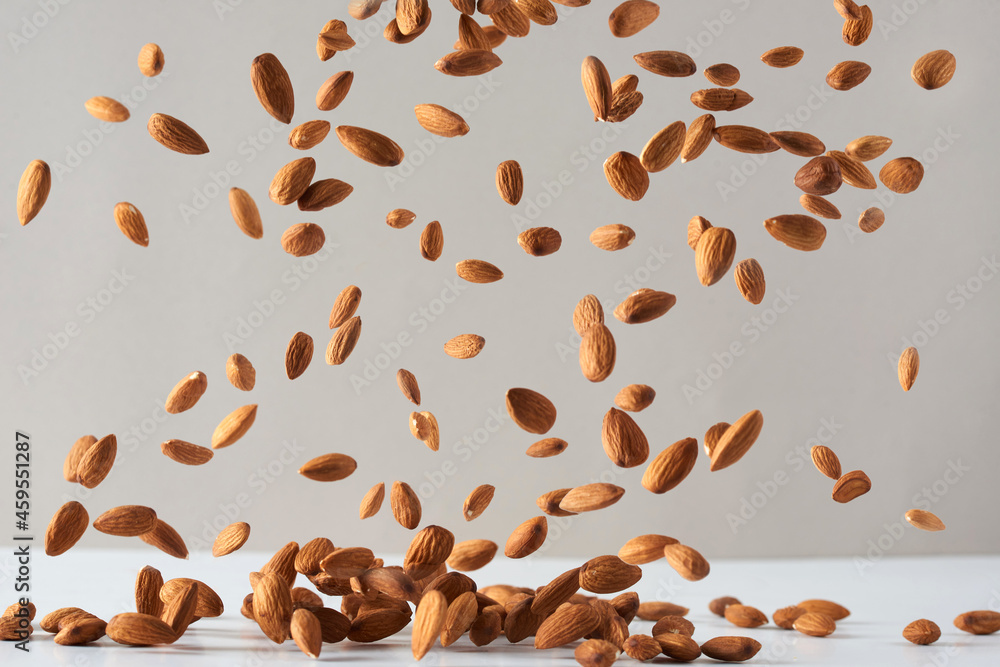 Flying almond nuts. Fresh raw almonds fall on a white background.Flying ...