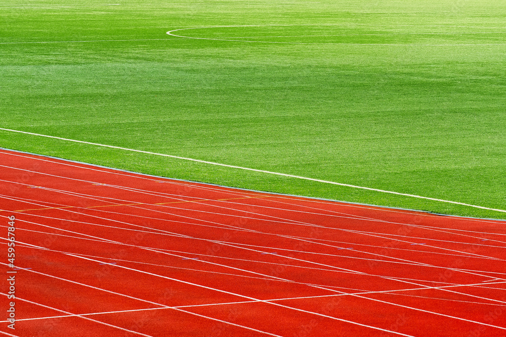 Red running track and green grass field on sports stadium. Close-up of ...