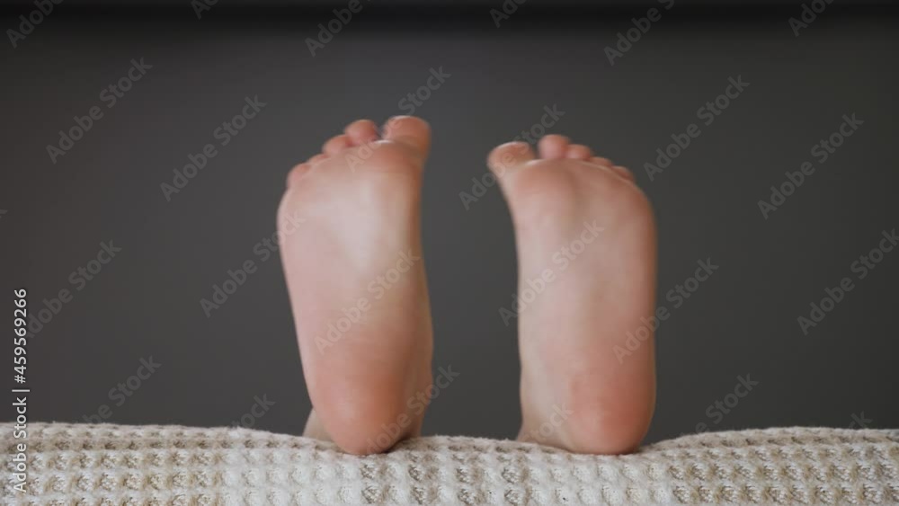 Bedtime child lying in sofa and move of music bare feet close up. Child ...