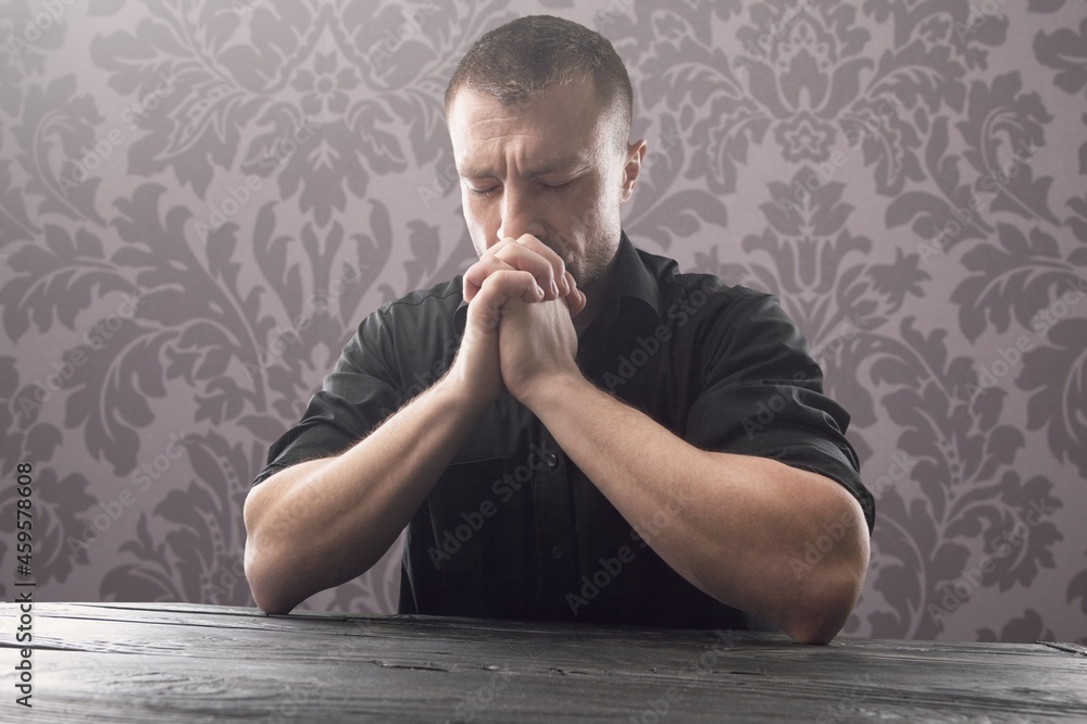 man praying to god with hands together praying with dark background ...