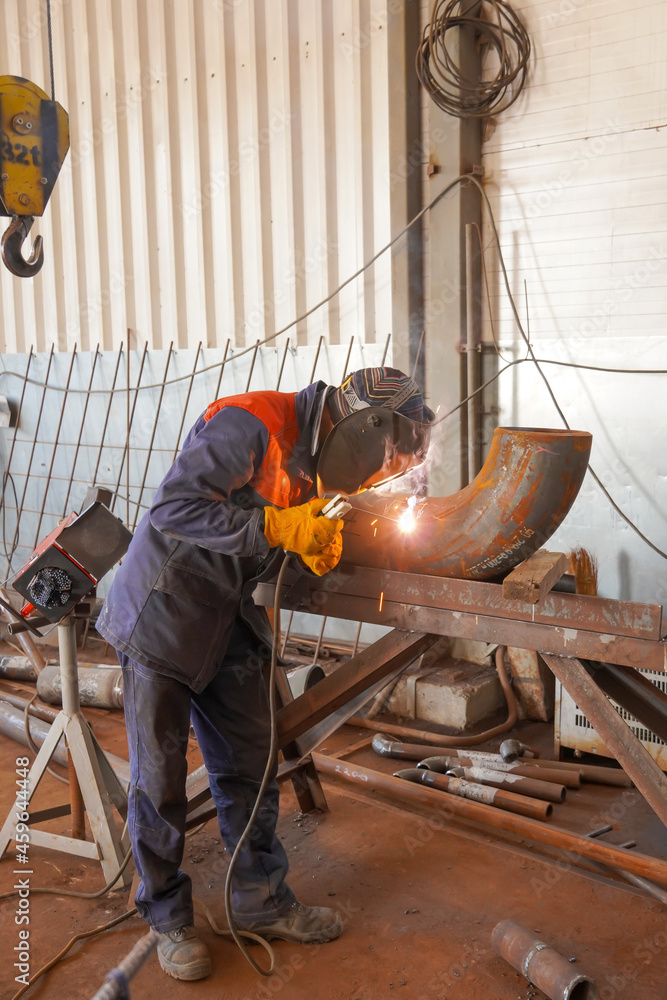 Welding production specialist welds with manual arc welding, welded ...