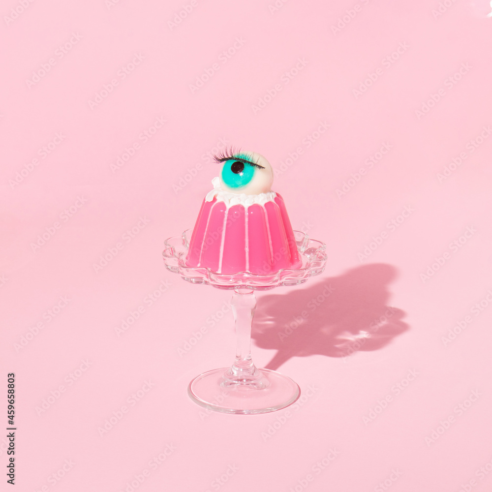 Creative layout with pink jelly on dish with eyeball figurine on pastel ...