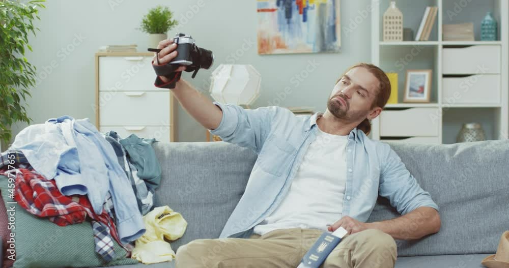 Young handsome caucasian male tourist sits at home on couch and is ...