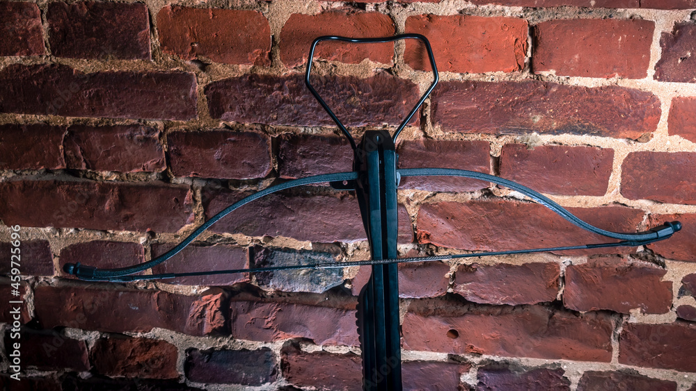 A modern compound crossbow handgun on the red brick wall background ...
