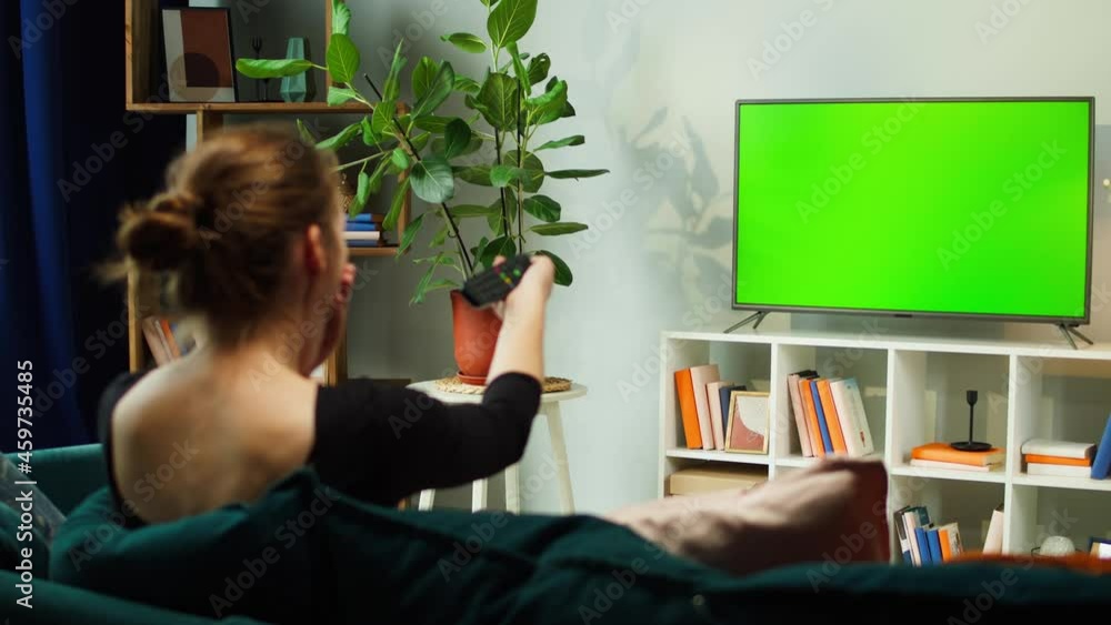 Woman watching TV with green screen in living room back view. Female ...