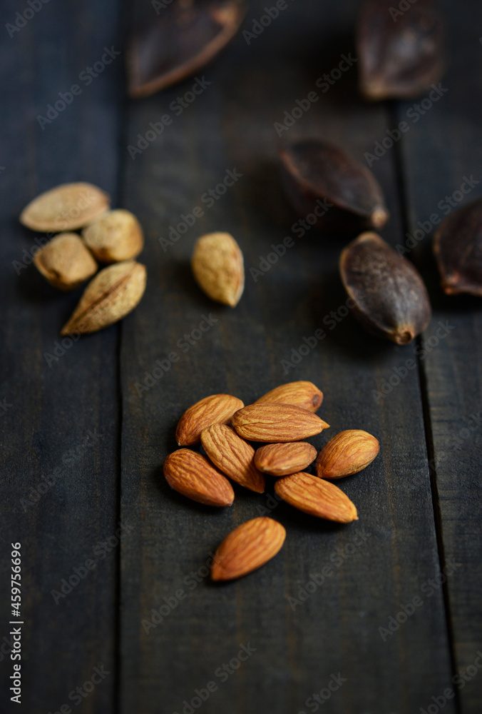 Few golden almonds placed on wooden background with its hard shell ...