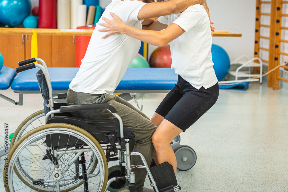 Disabled patient and female physiotherapist, exercise standing up and ...