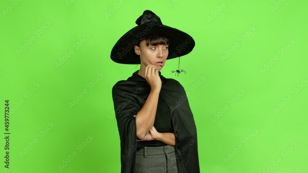 Young woman wearing witch hat having doubts and questioning an idea ...
